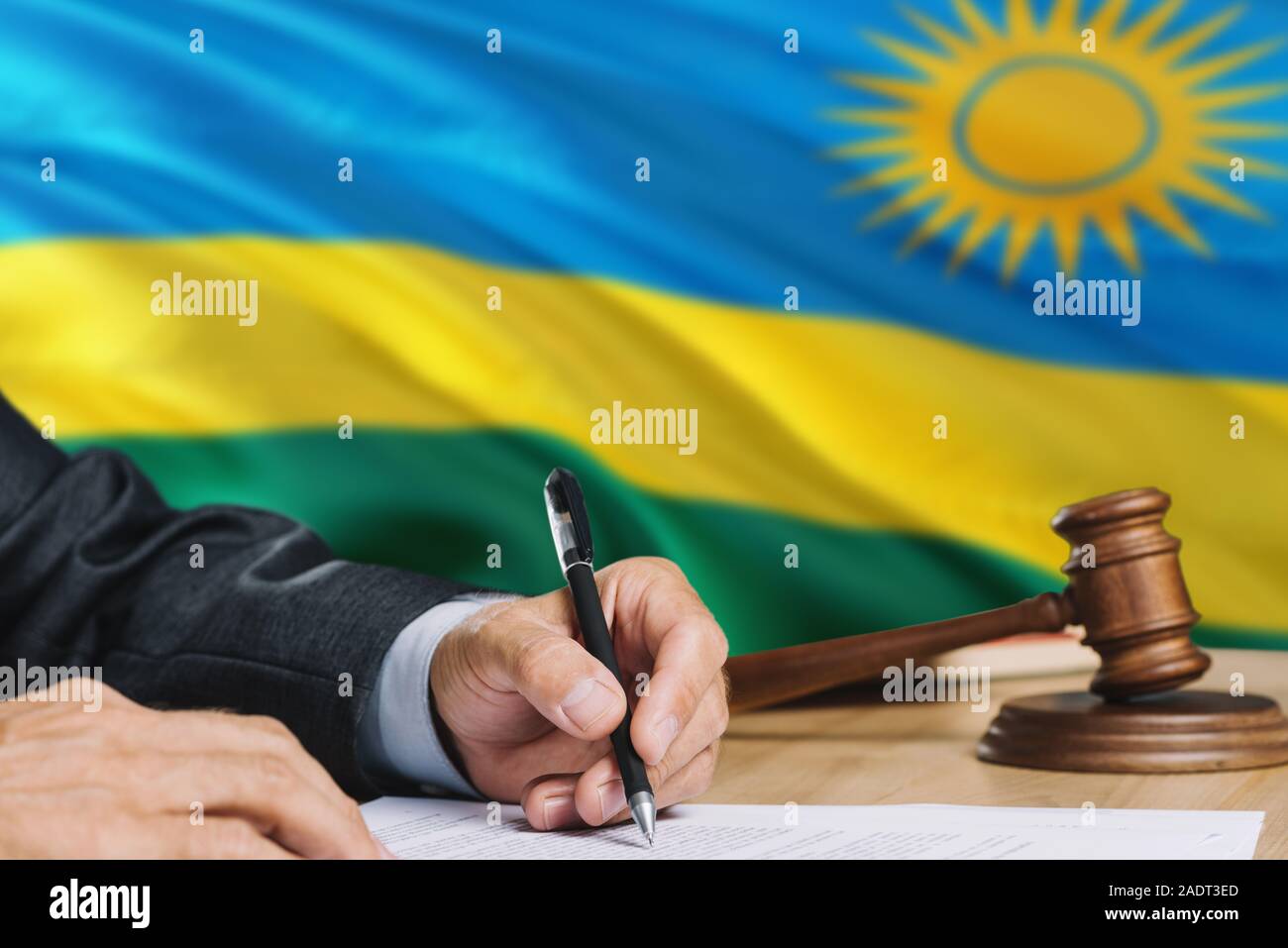 Judge writing on paper in courtroom with Rwanda flag background. Wooden ...