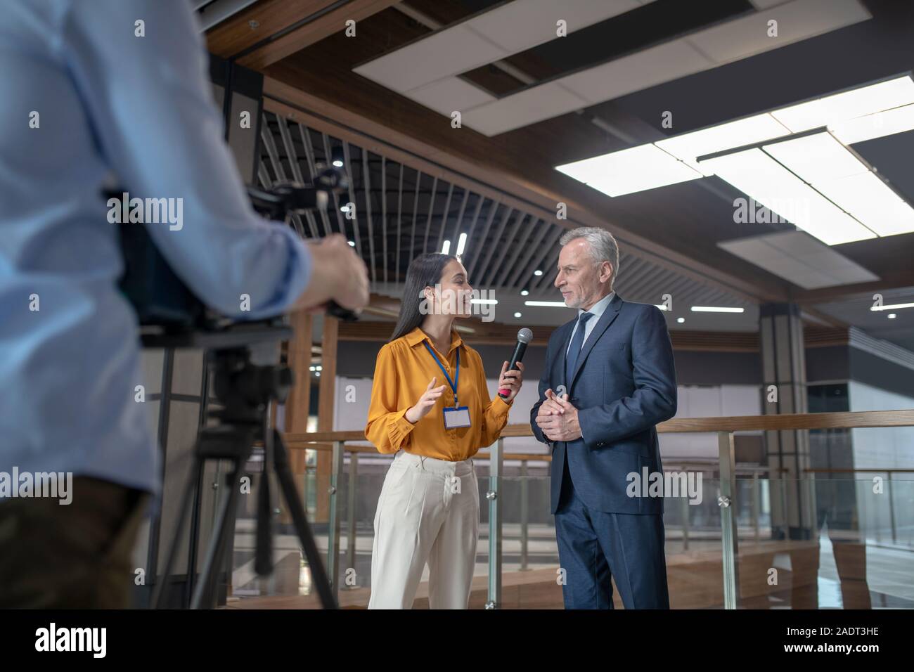 Asian female reporter asking questions to grey-haired man Stock Photo ...