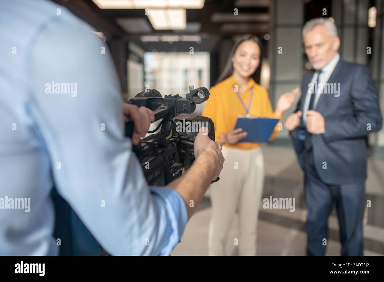 Asian female reporter in beige pants smiling nicely Stock Photo - Alamy