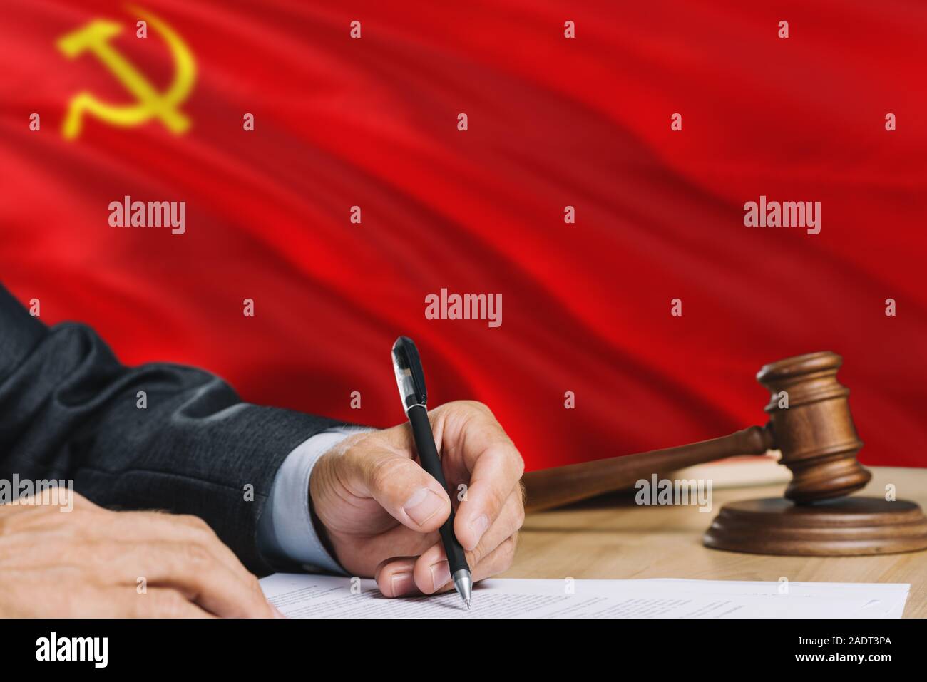 Judge writing on paper in courtroom with Soviet Union flag background ...