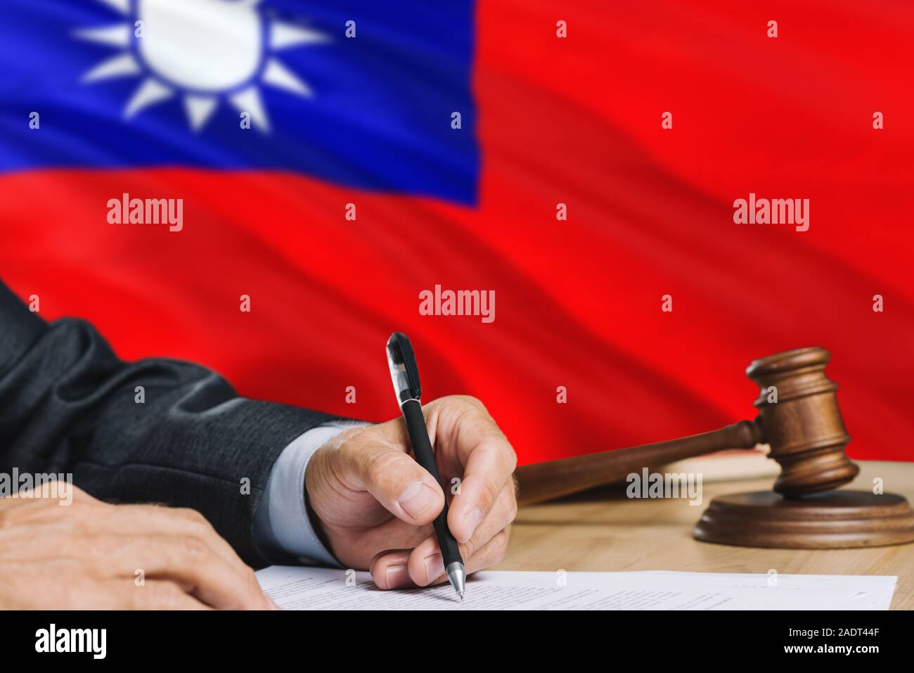 Judge writing on paper in courtroom with Taiwan flag background. Wooden ...