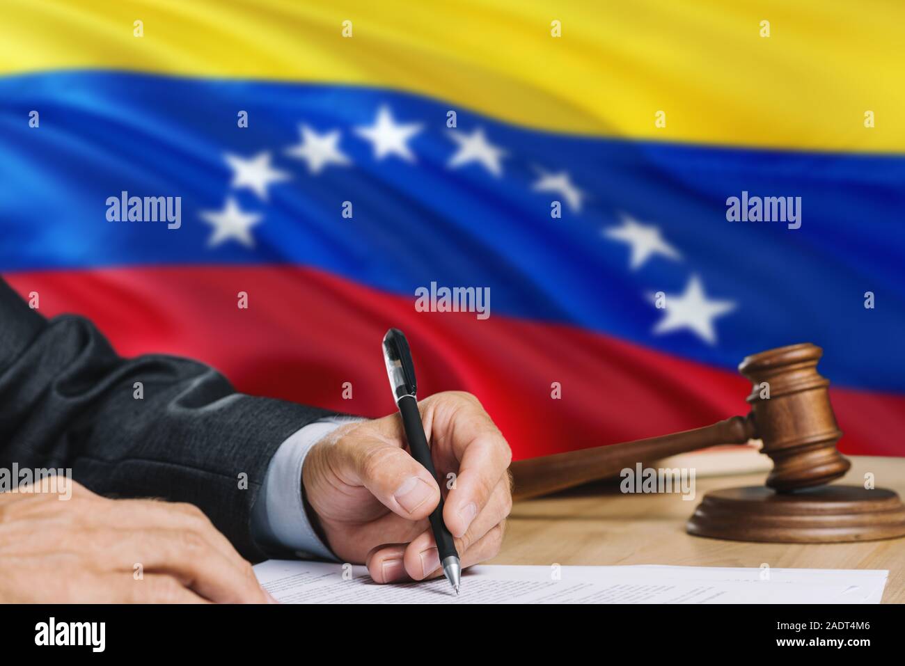 Judge writing on paper in courtroom with Venezuela flag background ...