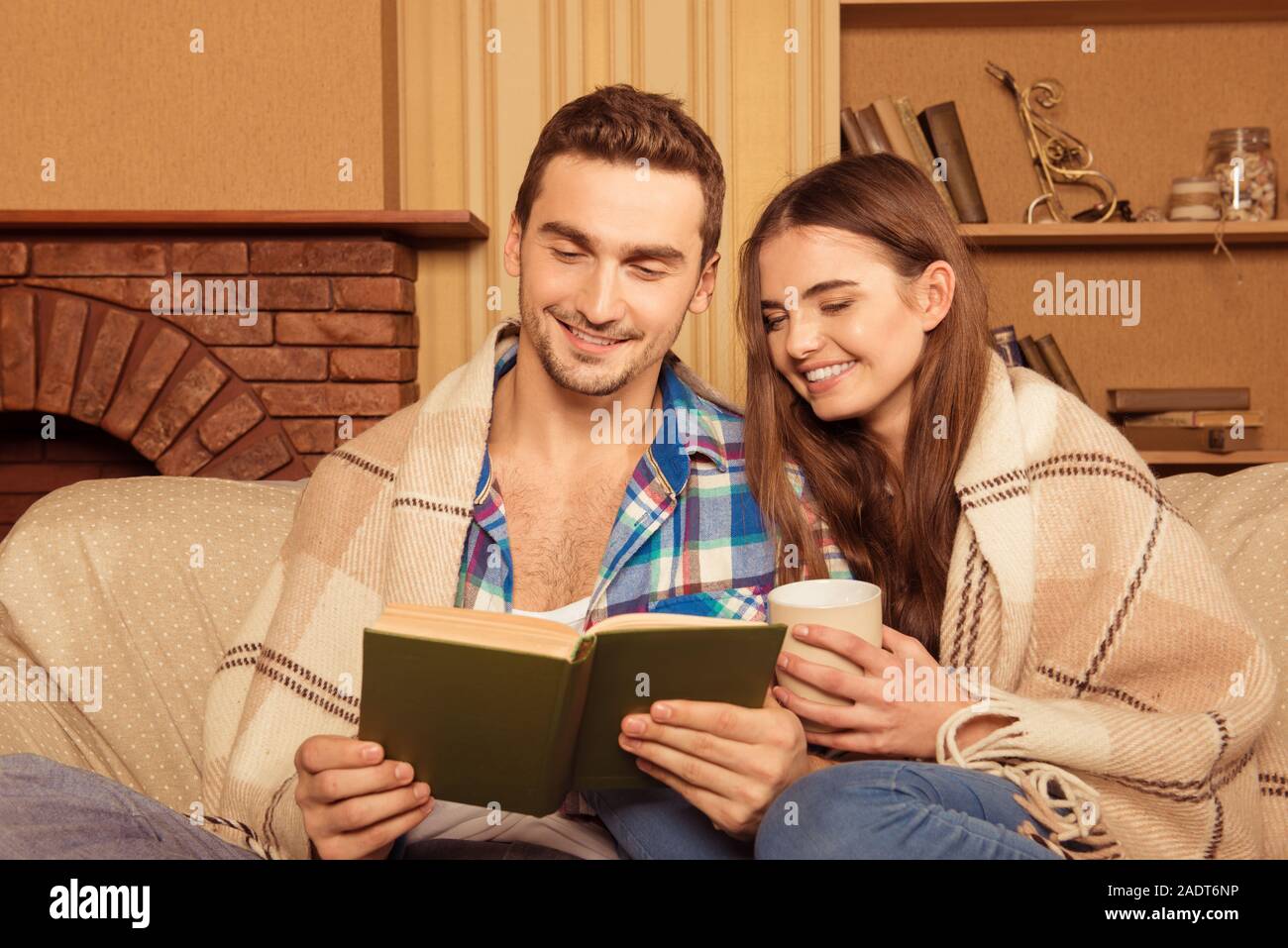 Young cute couple reading together under the plaid Stock Photo - Alamy