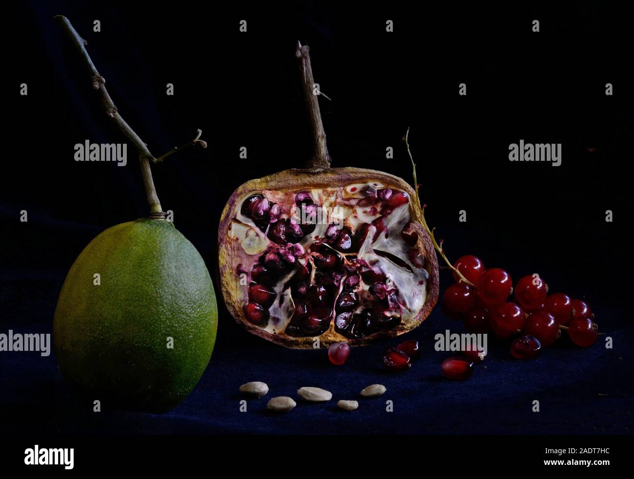 green lemon and pomegranate with their spilled seeds on a blue ...