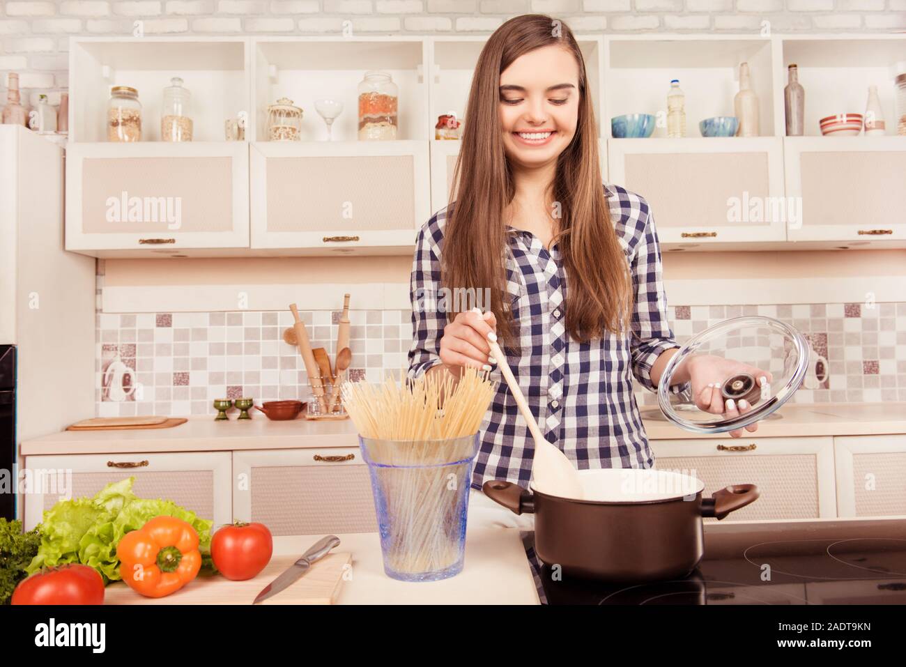 Happy young woman boiling spaghetti in the kitchen Stock Photo - Alamy