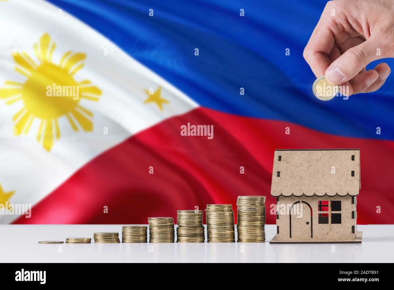 Man holding coins putting in wooden house moneybox, Philippines flag ...