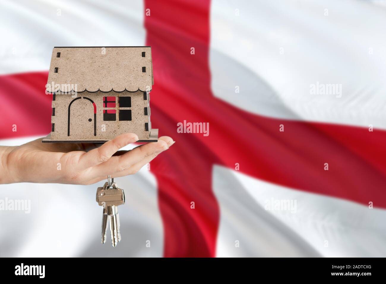 Woman hand holding wooden house and keys with hand. England flag with ...