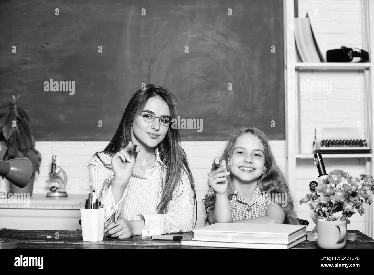 Little girl and woman sit at desk. School education. Studying together ...