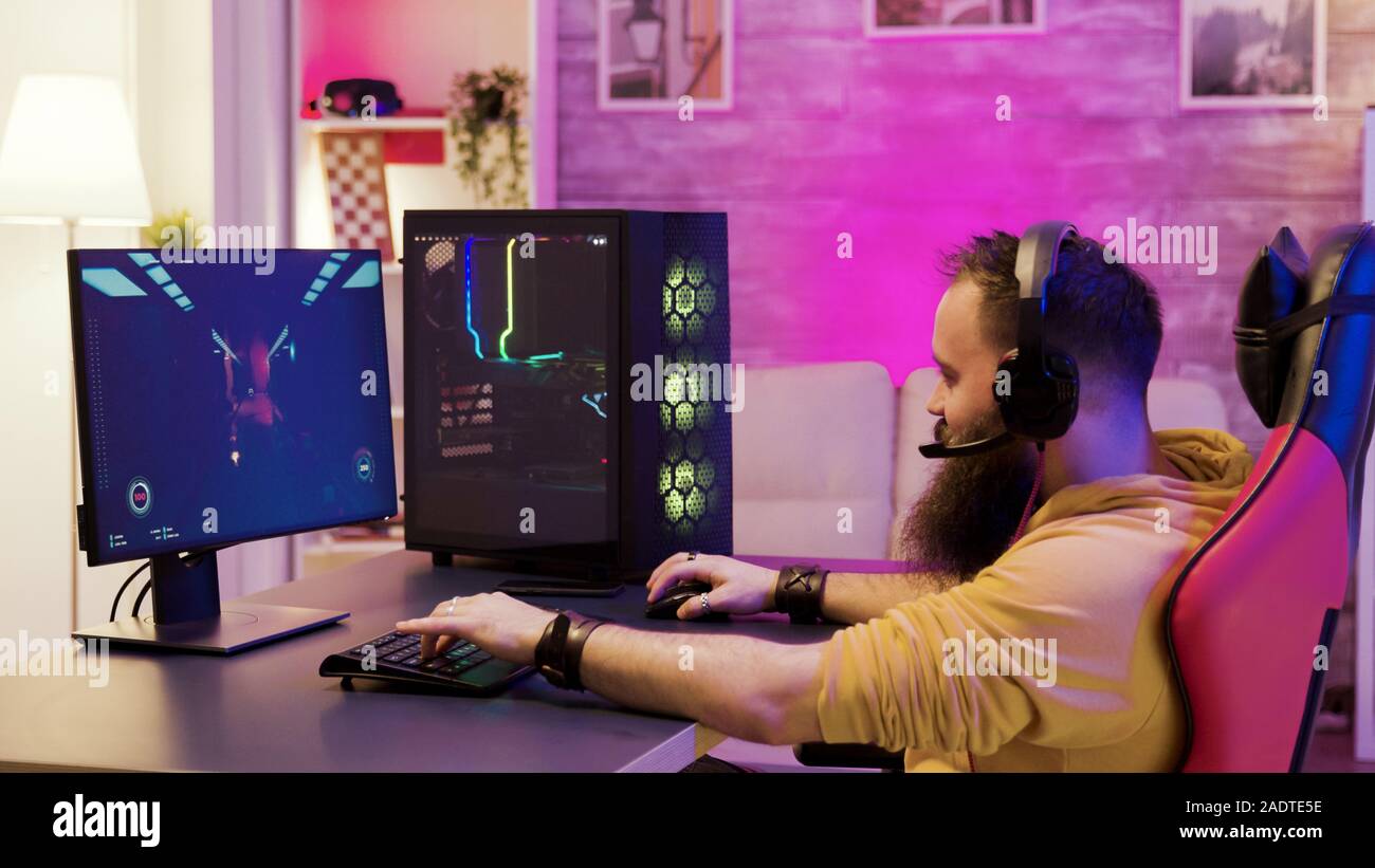 Bearded man playing online video games on his pc and talking with ...