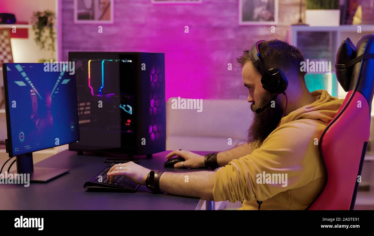 Hipster man playing professional video games in his room with colorful ...