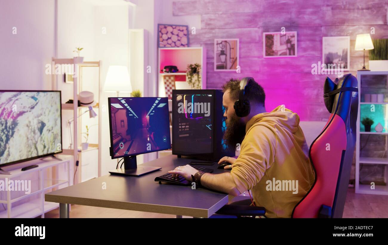 Successful man playing online video games in a room with colorful neons ...