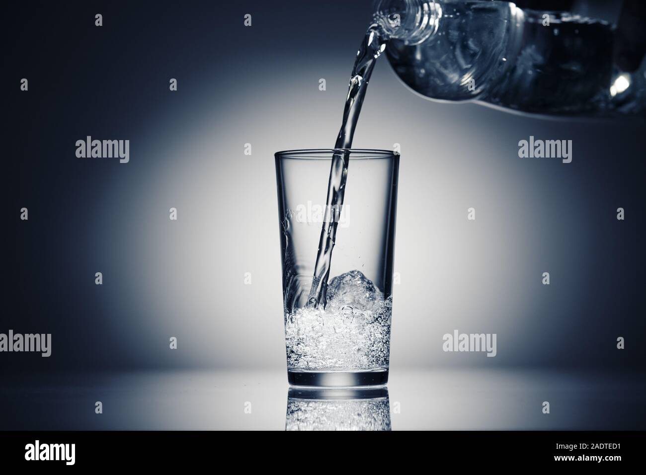 pouring sparkling water in a glass on a dark blue background Stock Photo - Alamy