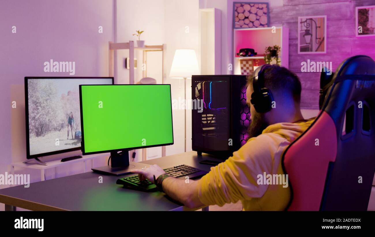 Man in his room relaxing playing video games on computer with green ...