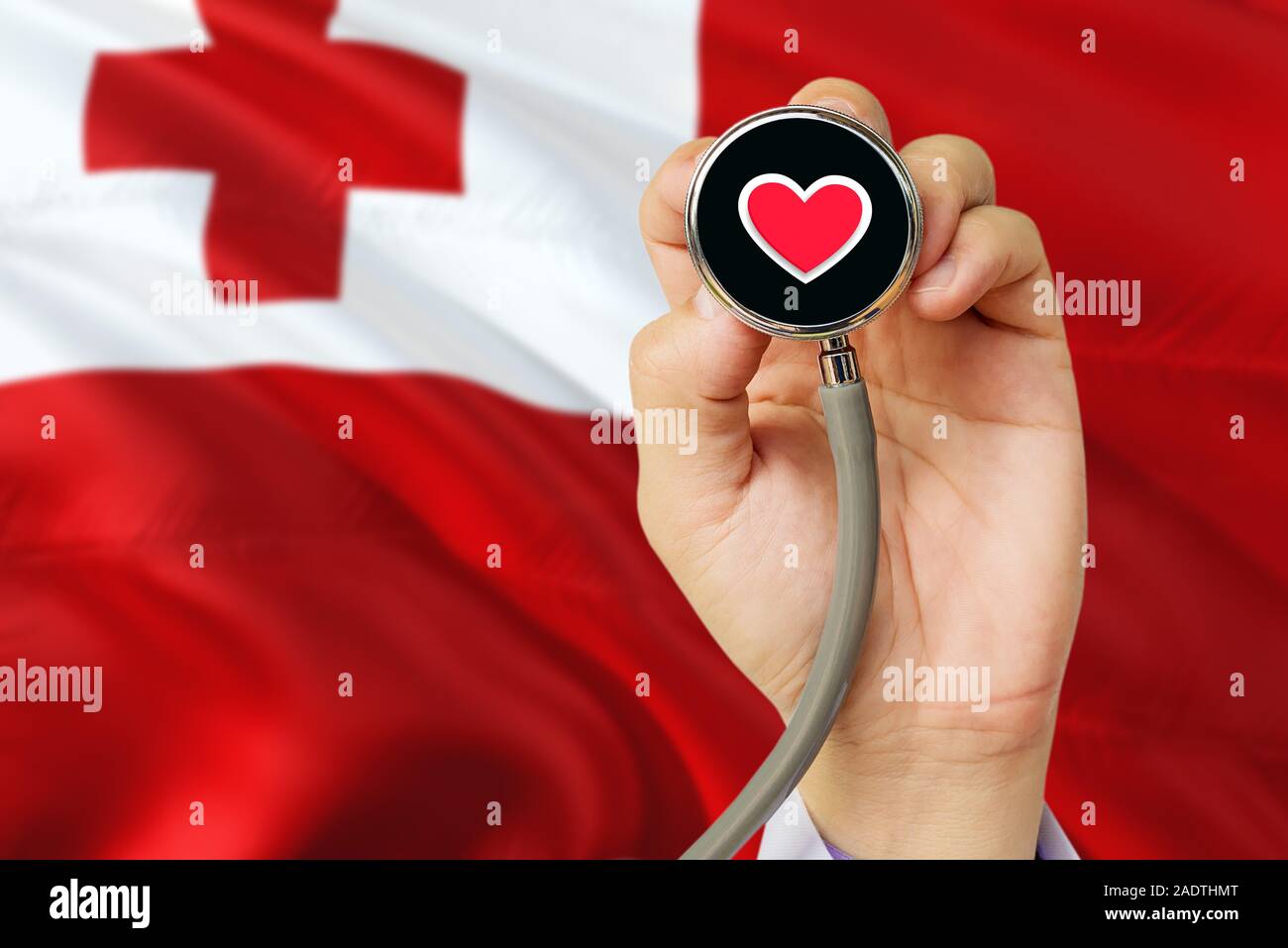 Doctor holding stethoscope with red love heart. National Tonga flag ...