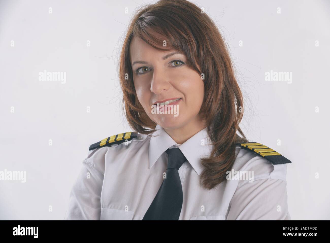Beautiful woman pilot wearing uniform with epauletes, standing isolated ...
