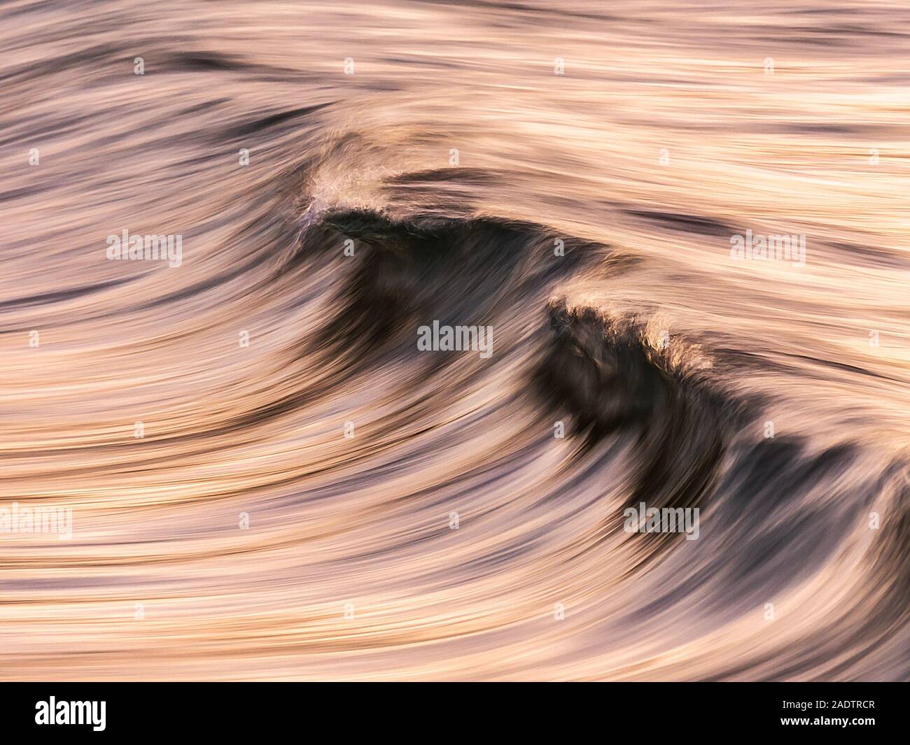 Photo of a wave at sunset with panning technique. This technique is ...