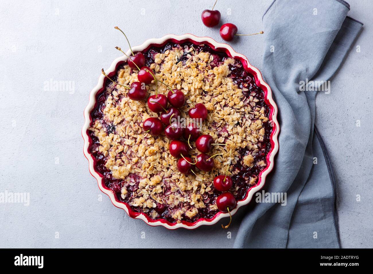 Cherry, red berry crumble in baking dish. Grey stone background. Top ...