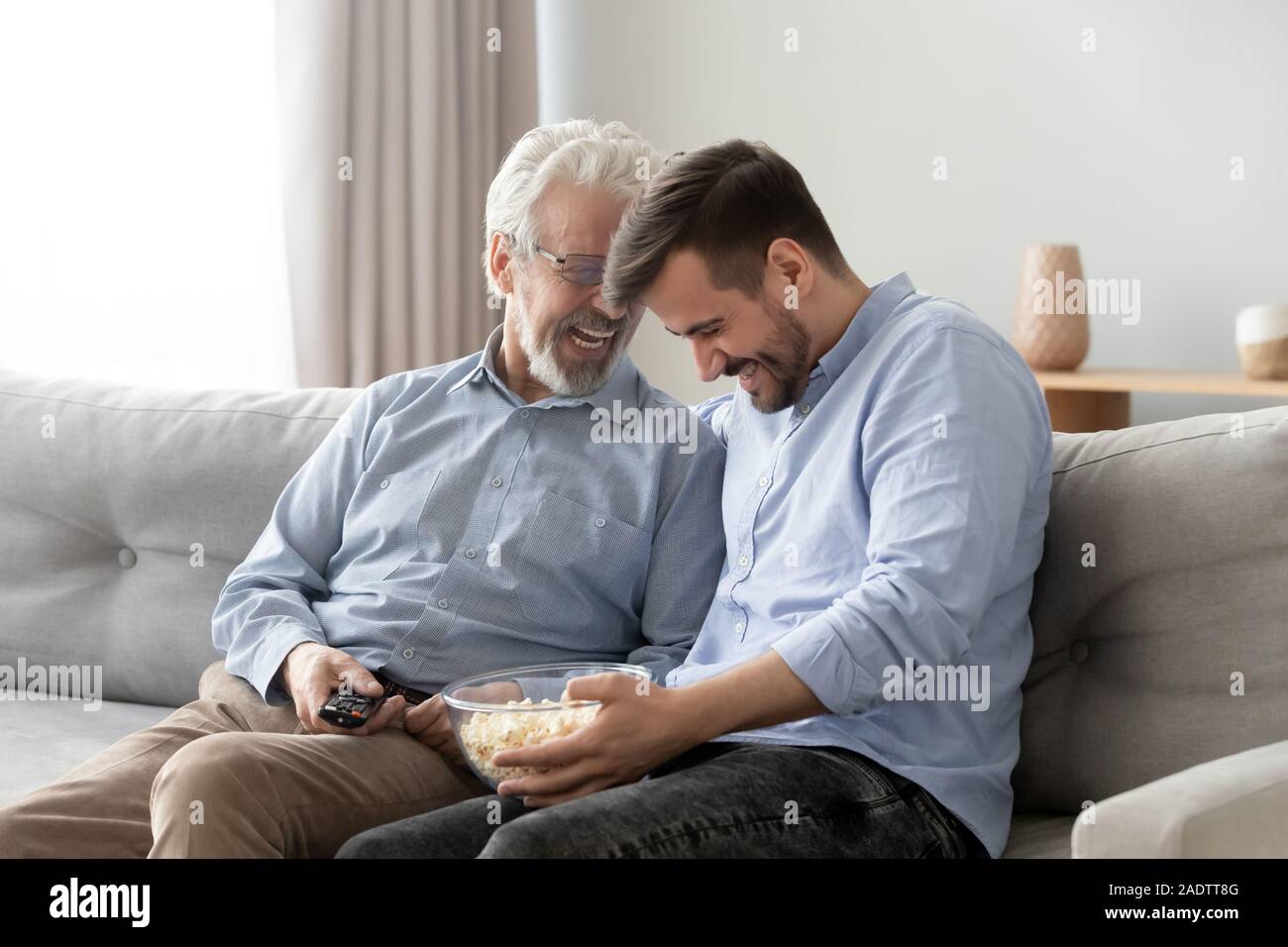 Elderly father grownup son laughing eating popcorn enjoy weekends ...