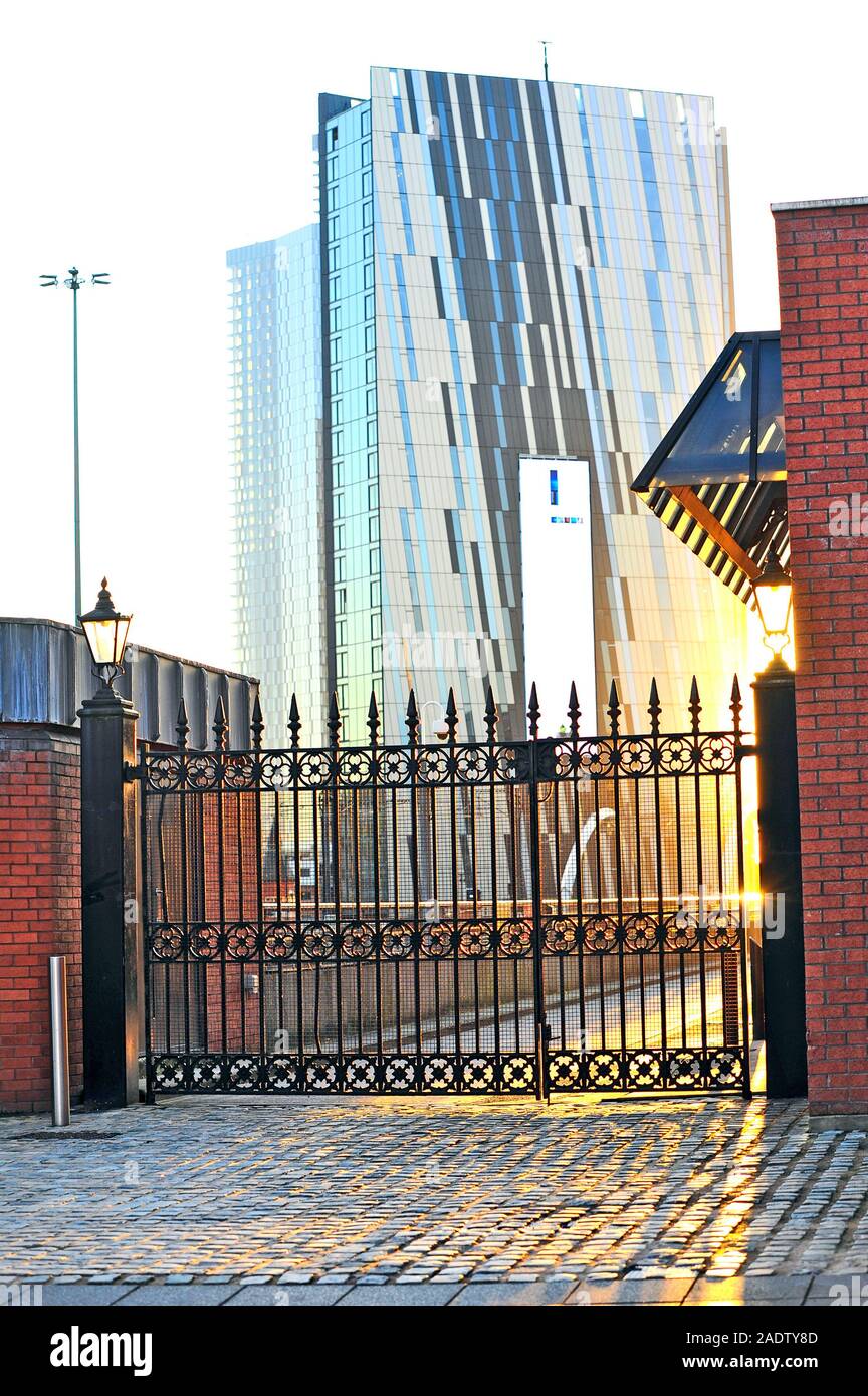 Ornate wrought iron gate against setting sun and modern apartment block ...