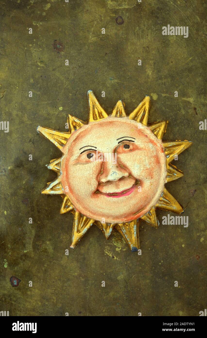 Plaster model of sun with smiley face and projecting flames or rays ...