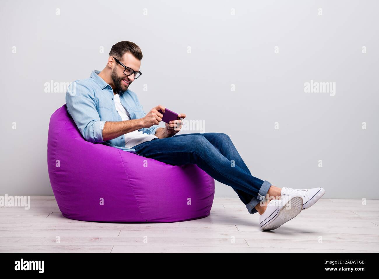 Full length profile photo of positive guy sitting comfy violet armchair ...