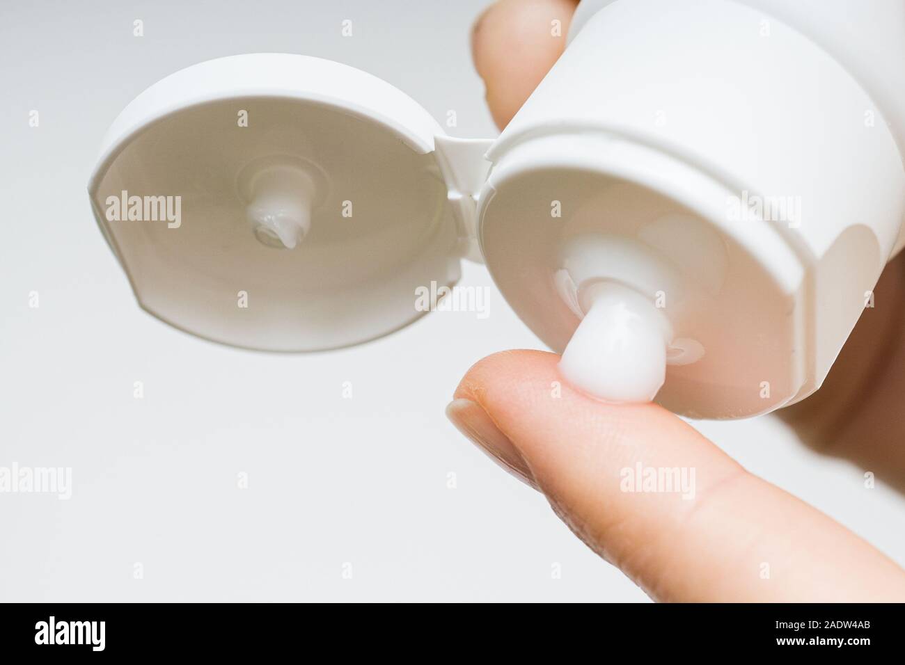 woman hands applying moisturizing cream to her finger skin from a tube ...