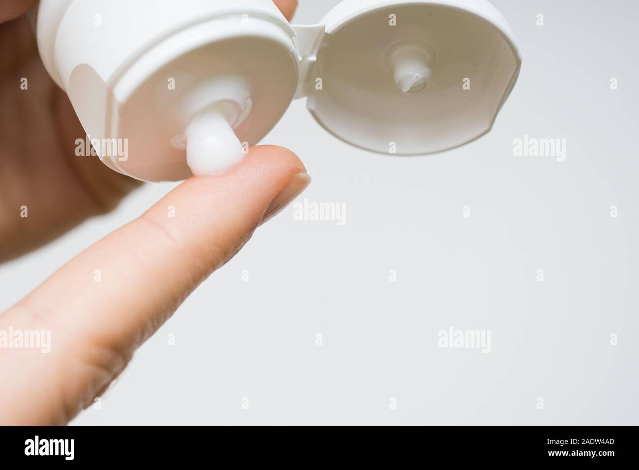 woman hands applying moisturizing cream to her finger skin from a tube ...