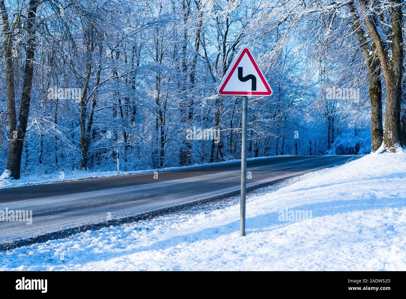 Winter driving concept - curvy winter road with warning sign Stock ...