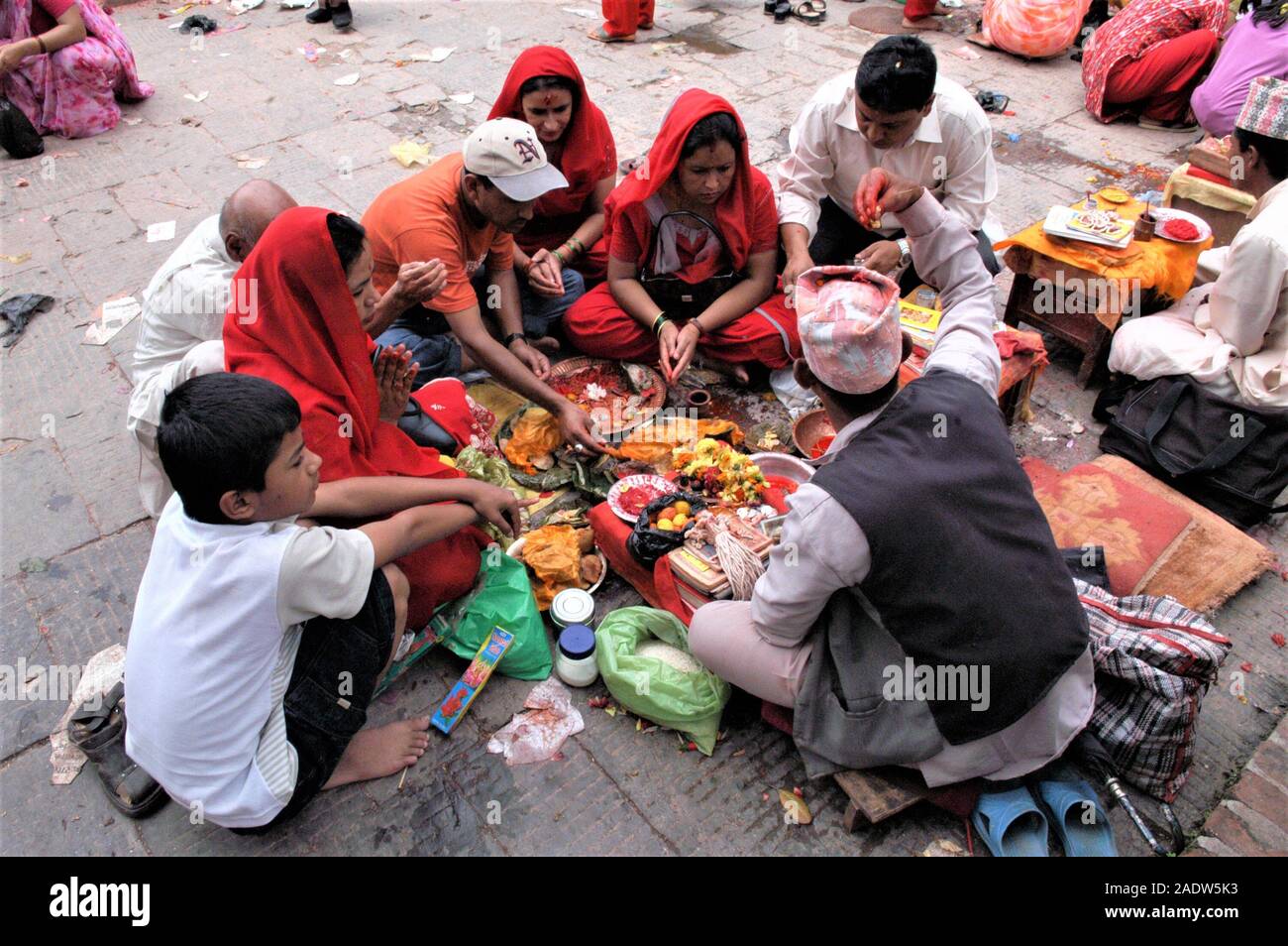 A GROUP OF PEOPLE SITTING IN A RELIGIOUS RITE WITH OFFERINGS TO THE ...