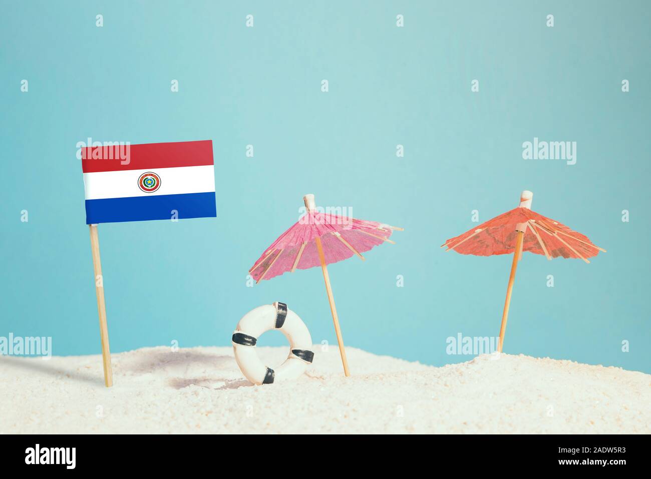 Miniature flag of Paraguay on beach with colorful umbrellas and life ...