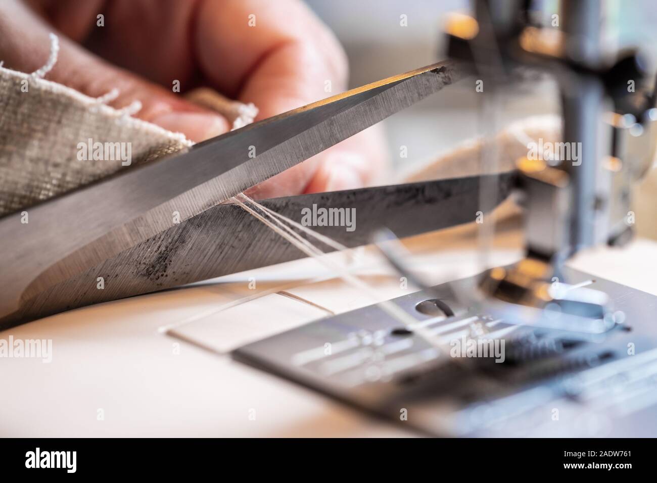 female hand with a scissors is cutting a thread at his sewing machine ...
