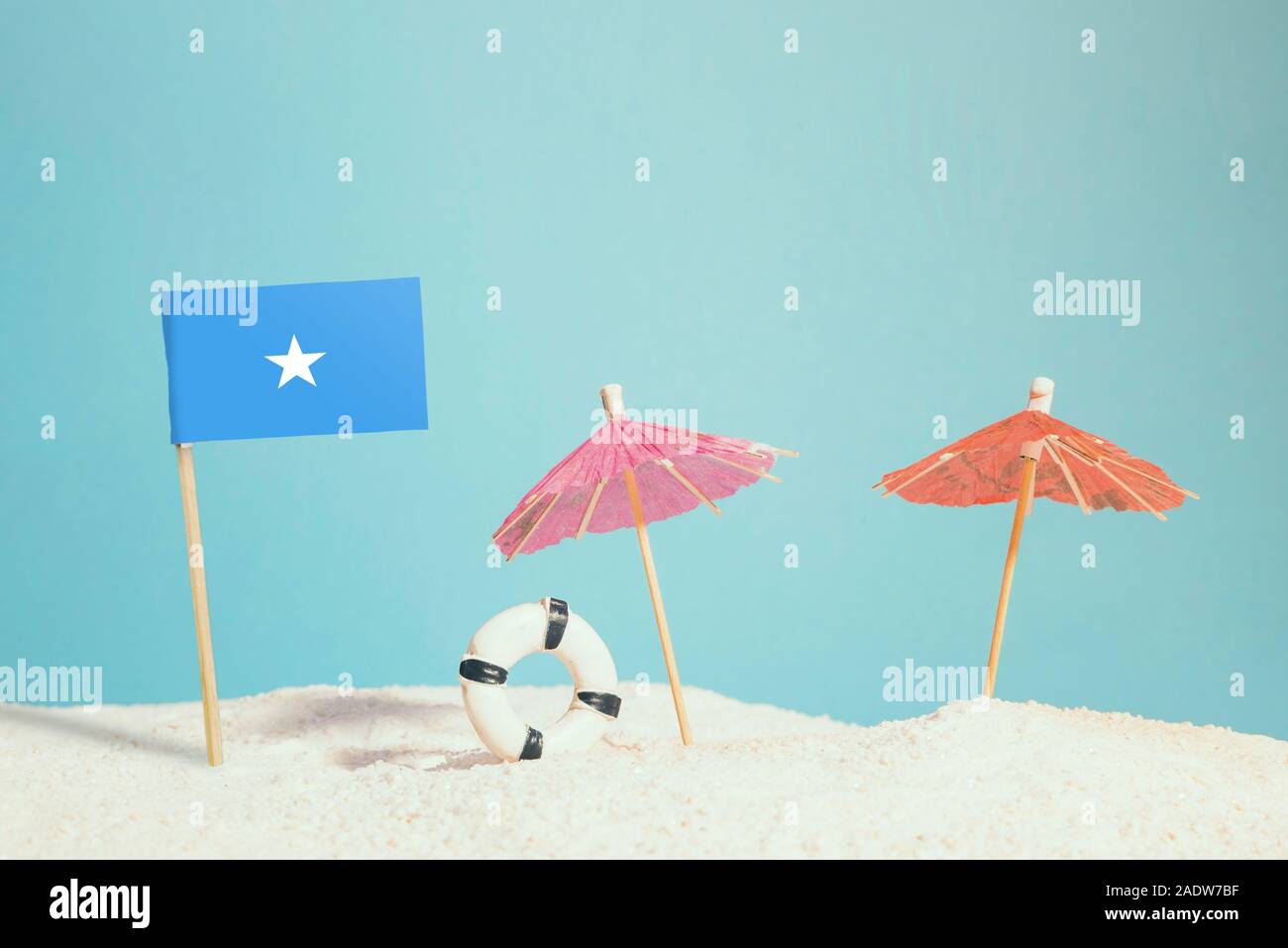 Miniature flag of Somalia on beach with colorful umbrellas and life ...