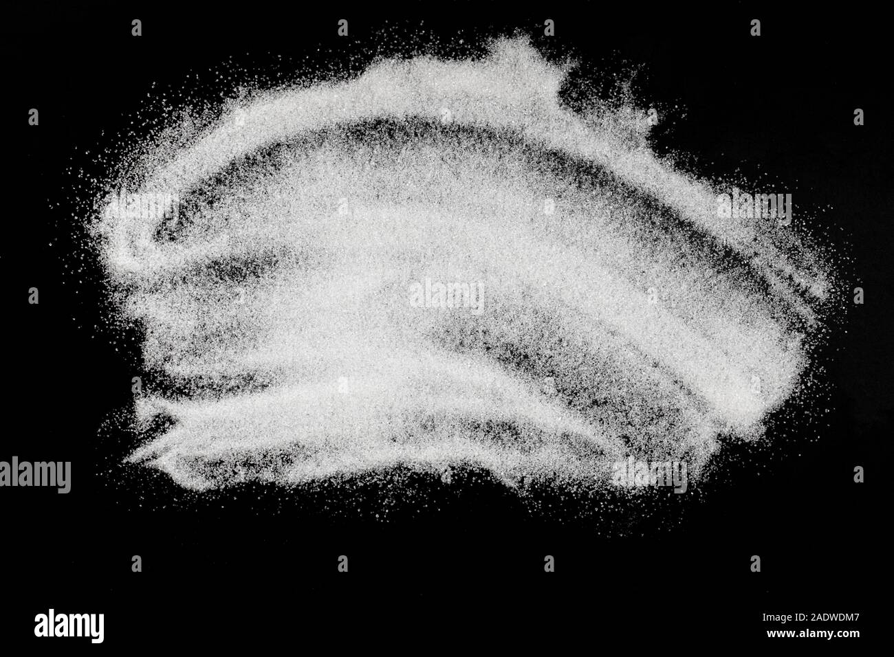 A pile of sugar sprinkled on a black background, backdrop. Abstract ...