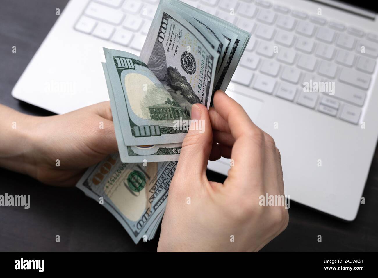 Hands counting money. Counting American dollars with hand on laptop ...