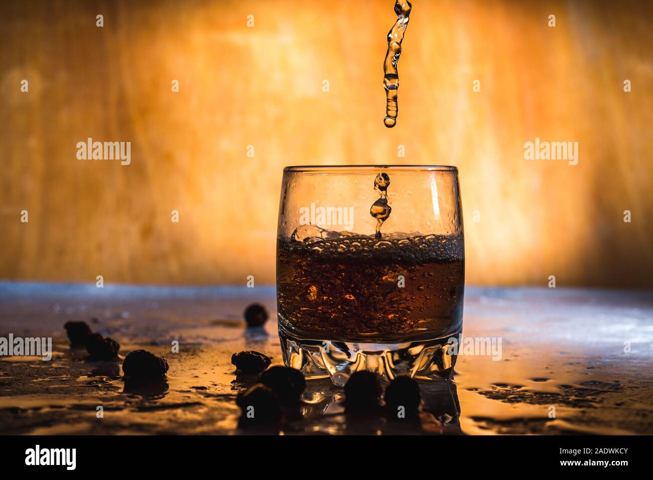 Splash of cold ice in glass of whiskey isolated on a light background ...