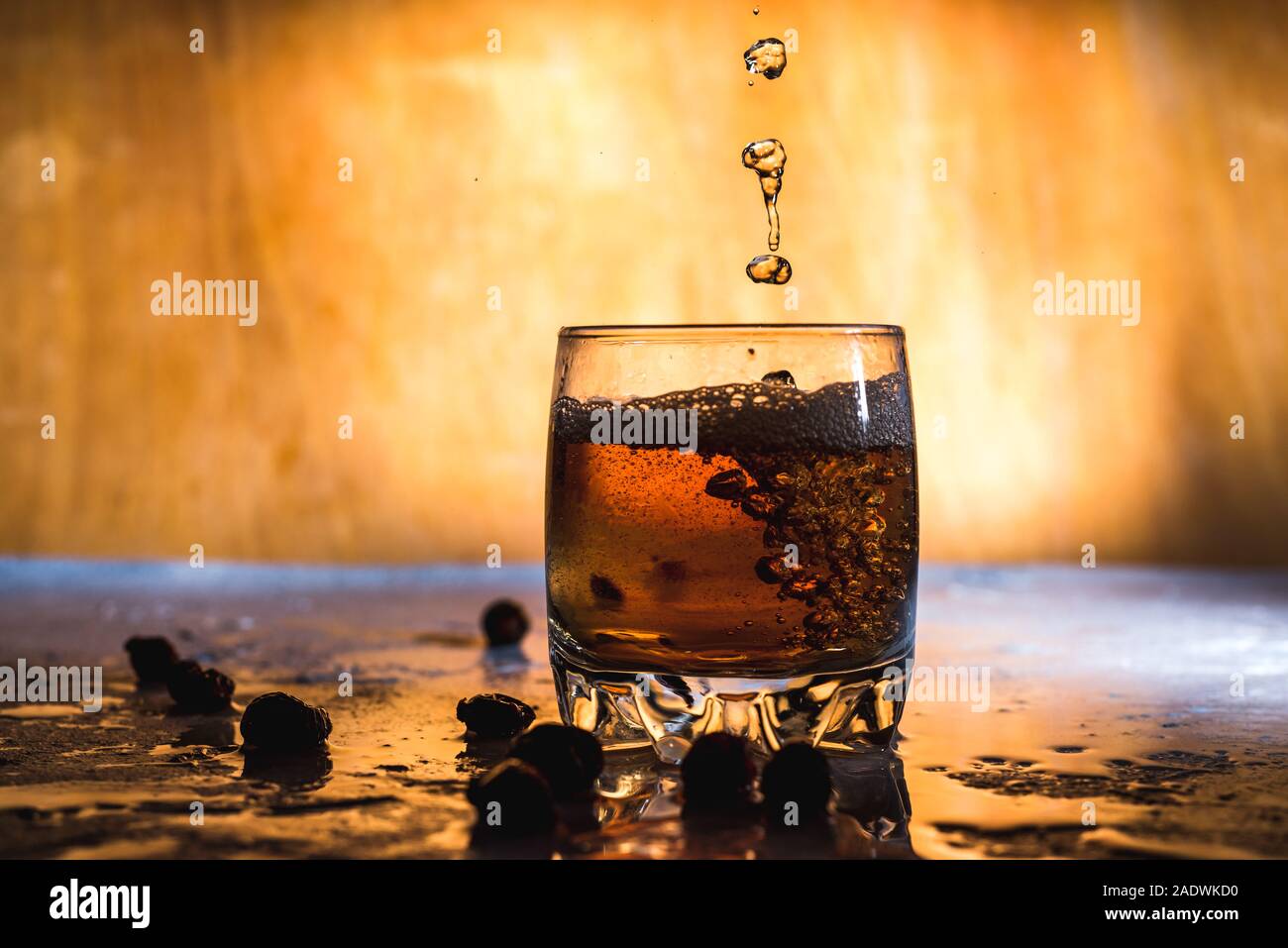 Splash of cold ice in glass of whiskey isolated on a light background ...