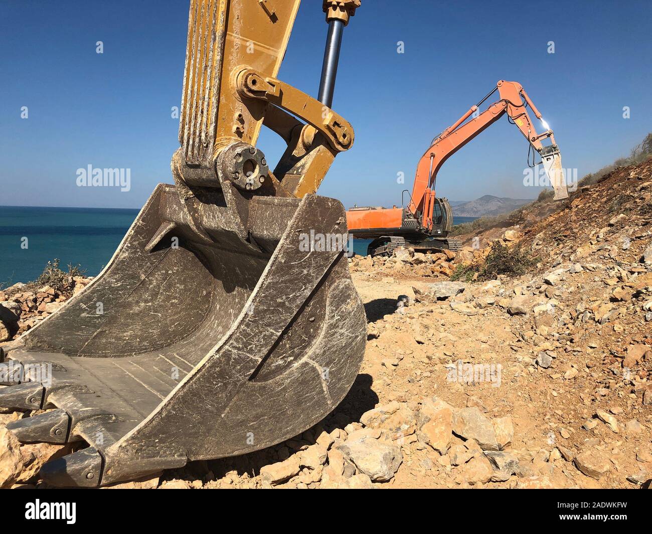 Excavator scoop moving a rock boulders during road construction on the ...