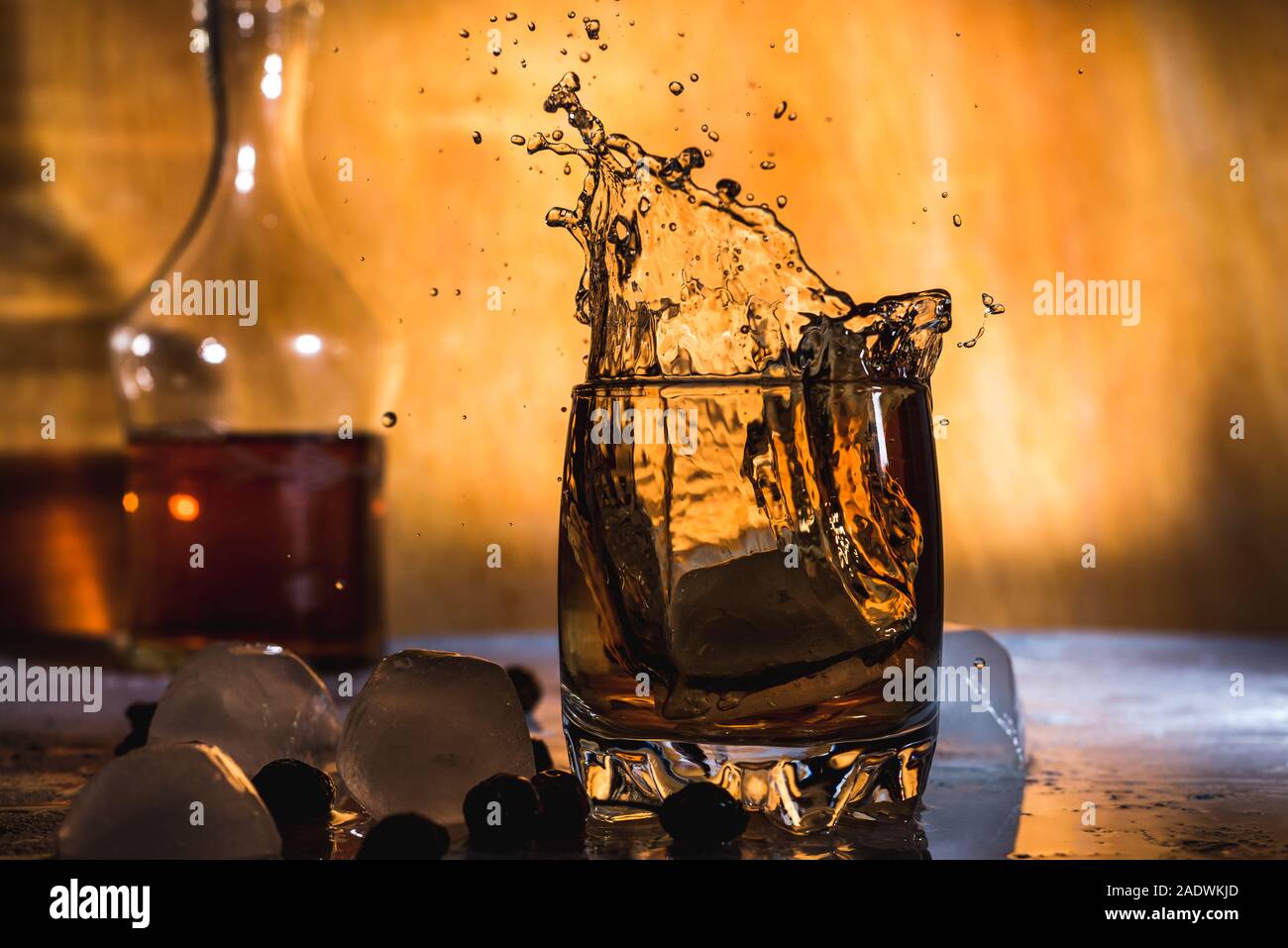 Splash of cold ice in glass of whiskey isolated on a light background ...