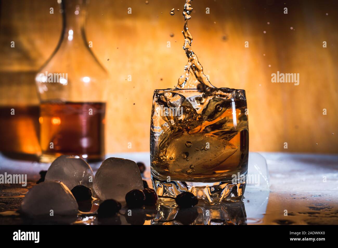 Splash of cold ice in glass of whiskey isolated on a light background ...