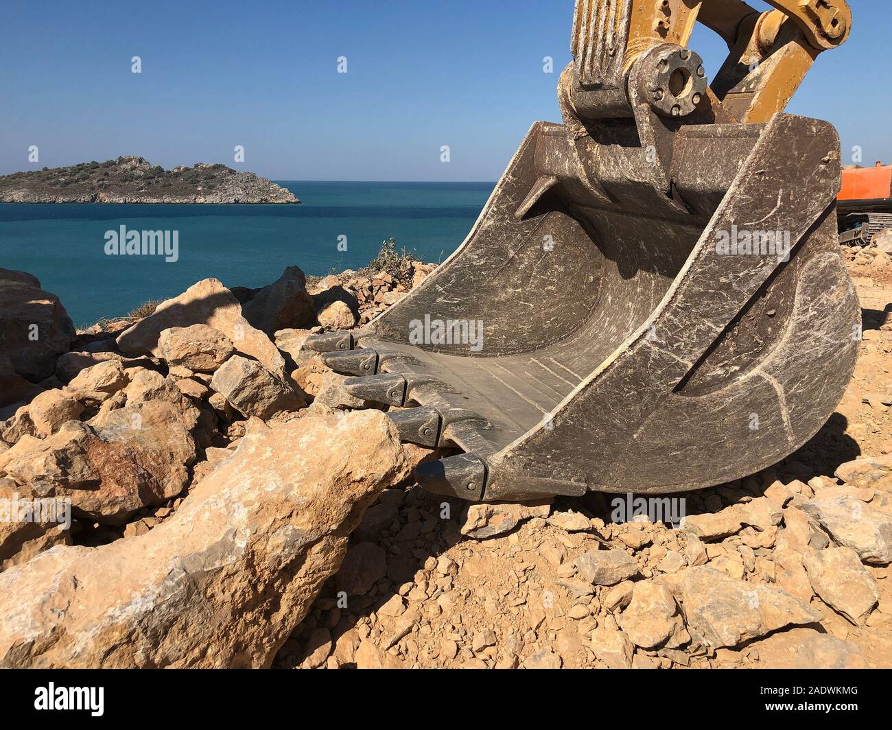 Excavator scoop moving a rock boulders during road construction on the ...