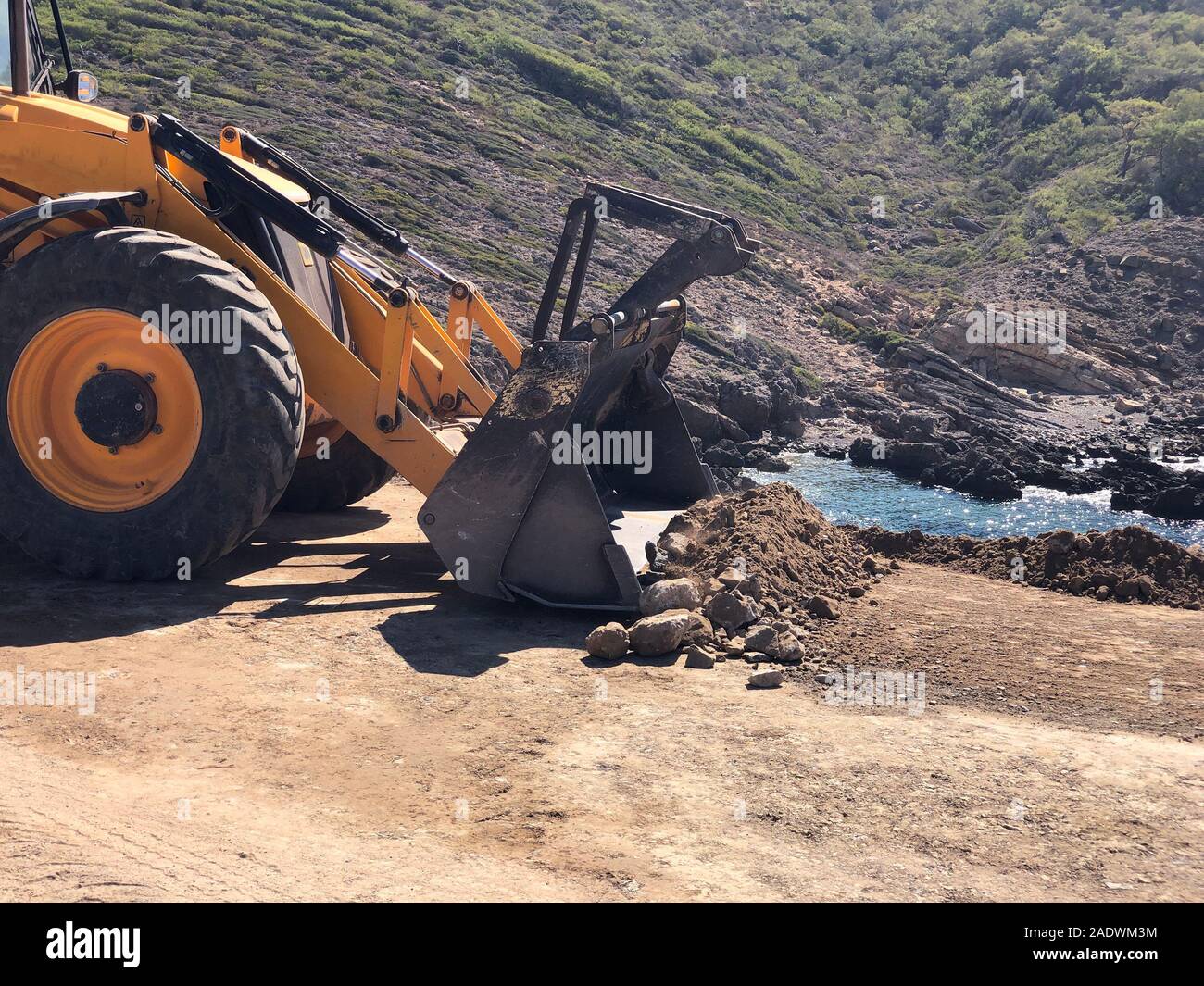 Yellow loader backhoe is planning a road surface during road ...