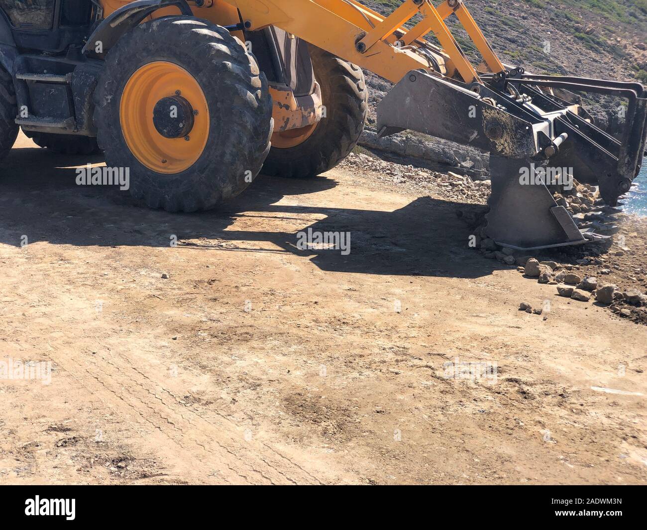 Yellow loader backhoe is planning a road surface during road ...