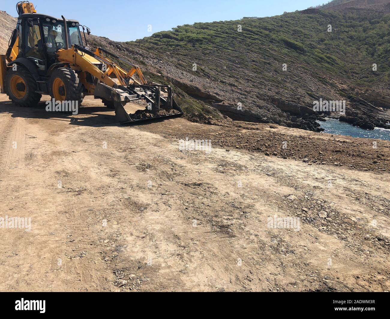Yellow loader backhoe is planning a road surface during road ...