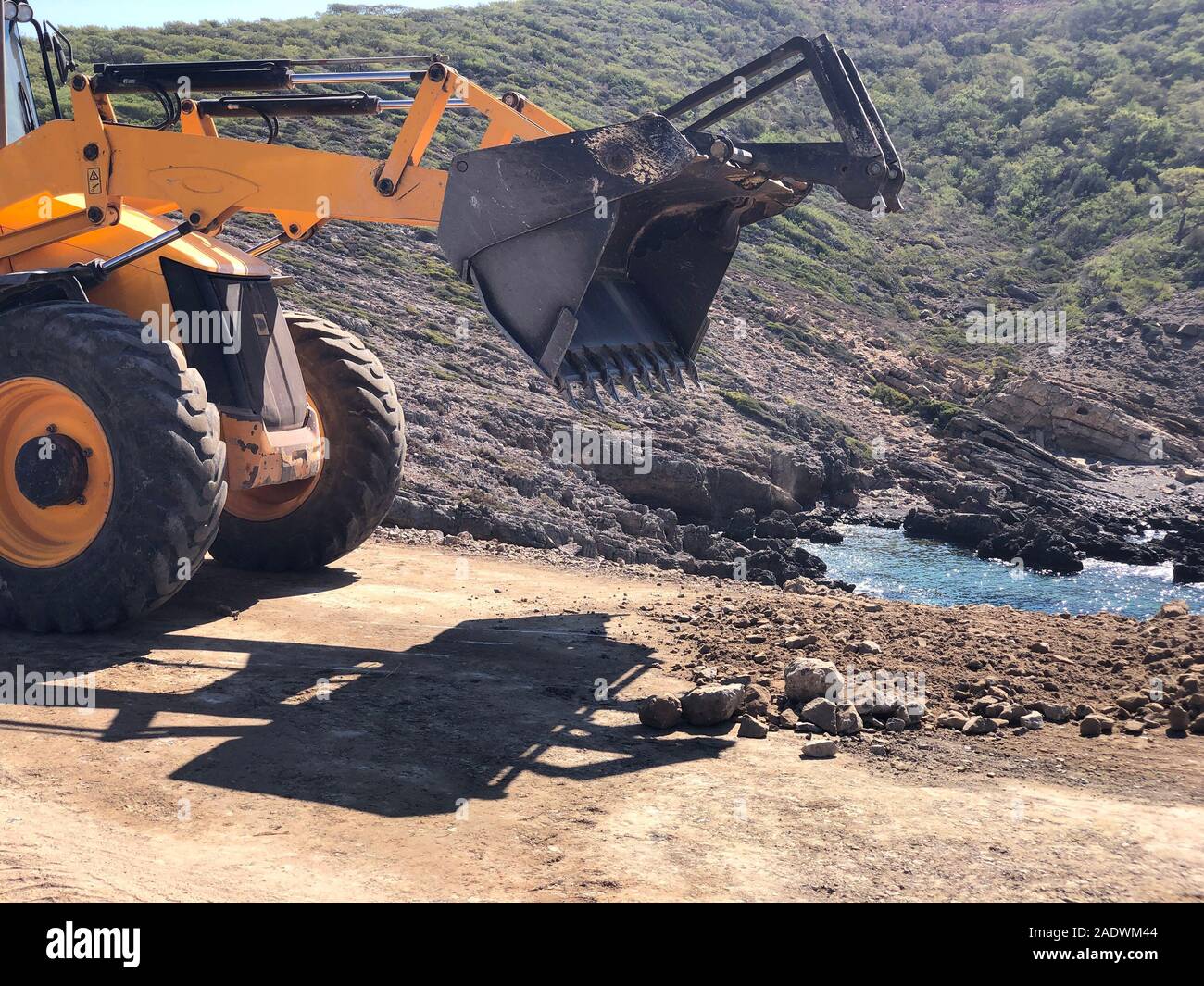 Yellow loader backhoe is planning a road surface during road ...