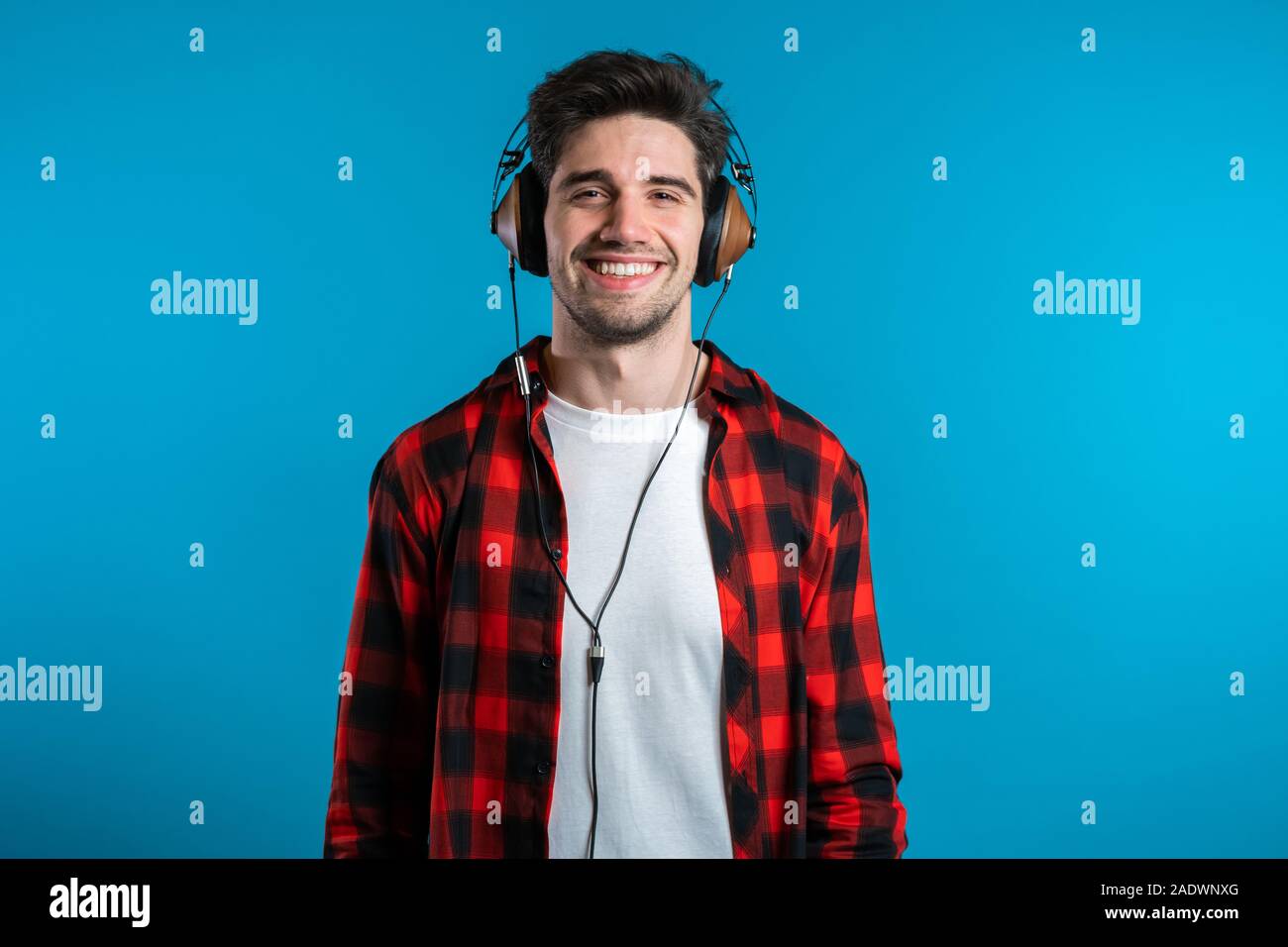 Handsome man with headphones dancing isolated on blue background. Party ...