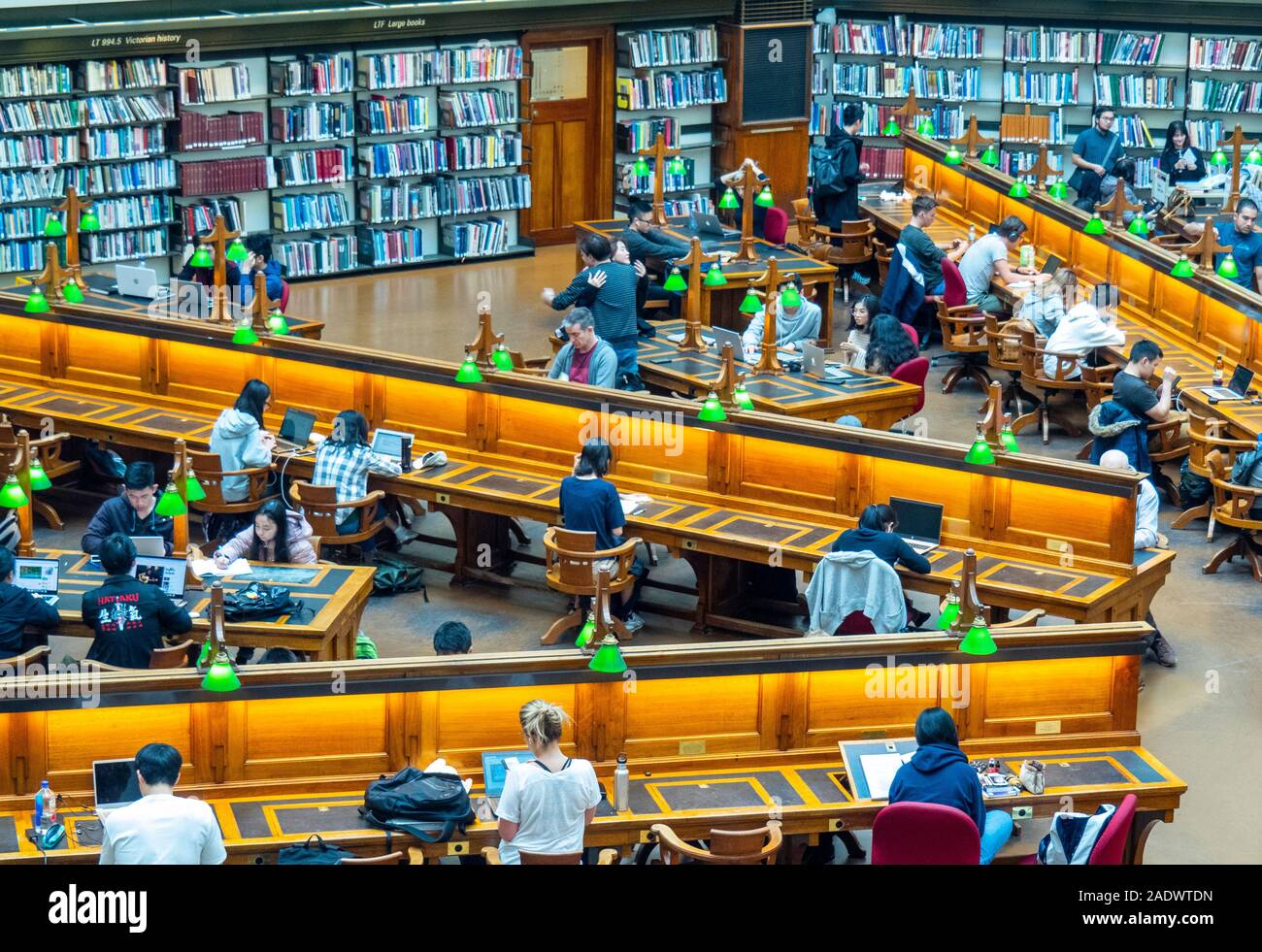 Wooden tables full of students studying in the La Trobe Reading Room of ...