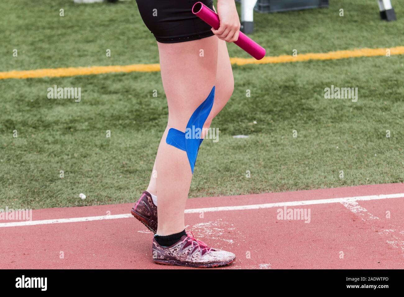 A high school sprinter is in lane one with tape around her knee ready ...