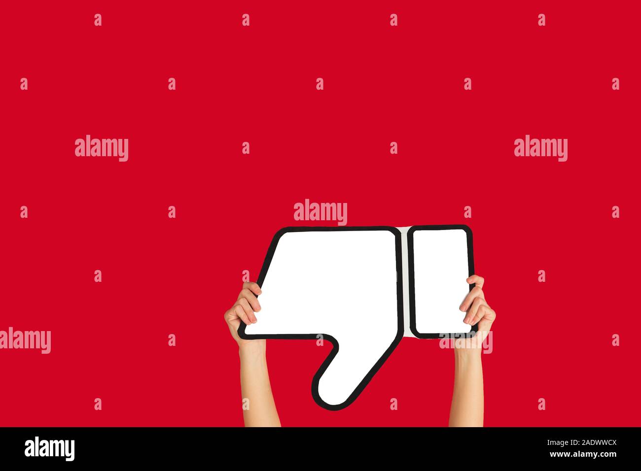 Hands holding the sign of dislike on red studio background. Negative ...