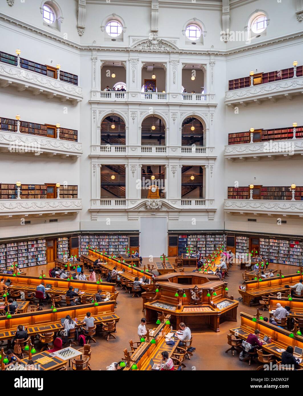 Wooden tables full of students studying in the La Trobe Reading Room of ...