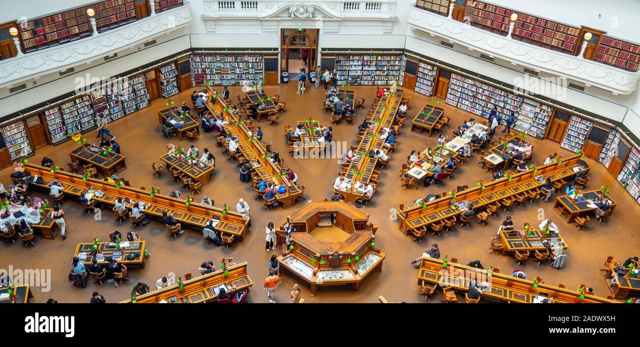 Wooden tables full of students studying in the La Trobe Reading Room of ...